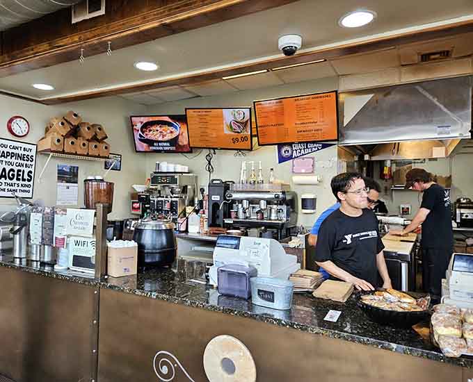 Behind that counter, the organized chaos of a busy bagel shop unfolds with practiced efficiency and genuine customer care.