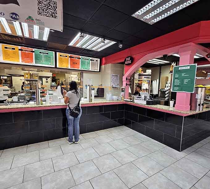The ordering counter where dreams are built one topping at a time, assembly-line style with colorful menu boards overhead.