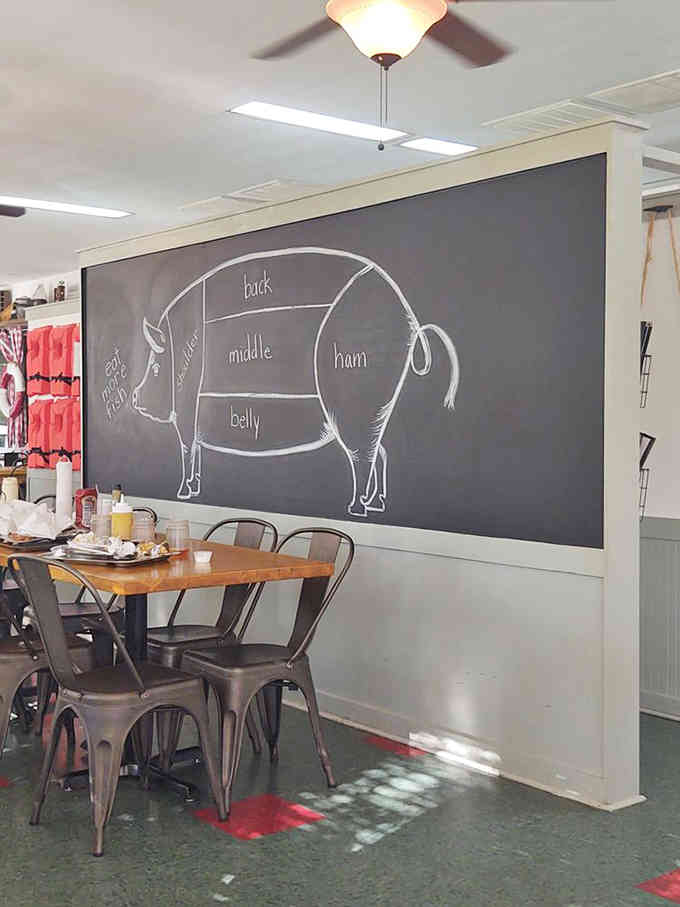 The chalkboard pig diagram educates while you wait, turning anatomy into appetite with labels for every delicious cut.