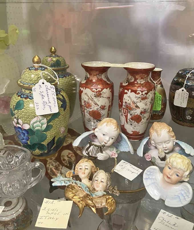 Delicate chinoiserie vases and cherubic figurines sharing shelf space like old friends at a very eclectic reunion.