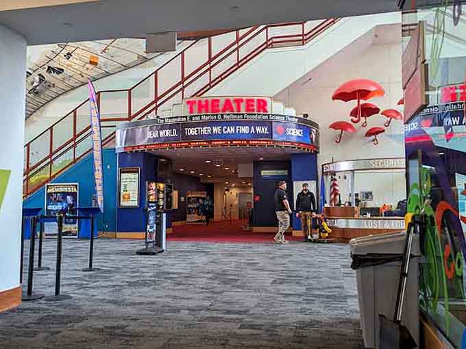 The theater entrance promises adventures in learning, complete with floating umbrellas that defy all reasonable expectations.