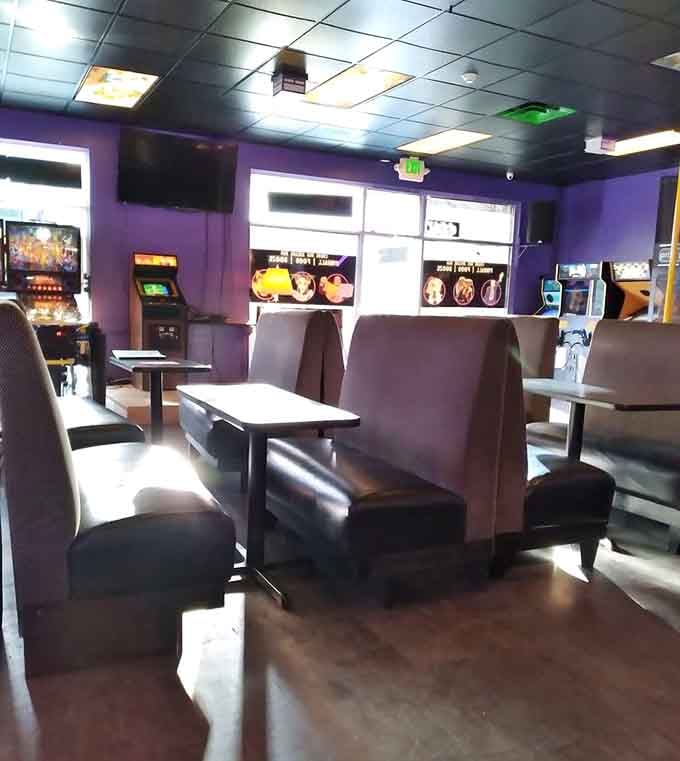 Purple walls and classic booths create cozy gaming nooks where friendships form over shared high score attempts.