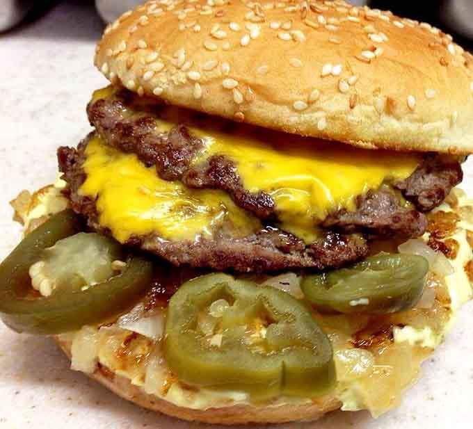 Sesame seeds on a toasted bun cradling crispy fish, proving that not everything here requires unhinging your jaw to eat.