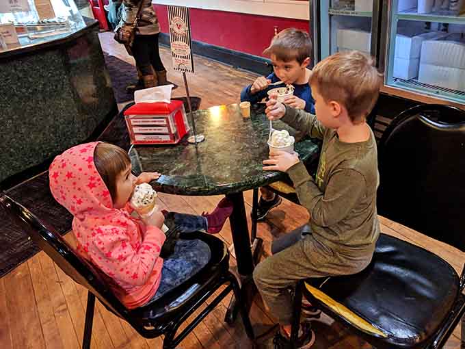 Three young connoisseurs enjoying their scoops at a vintage table, creating memories that'll last way beyond the sugar rush.
