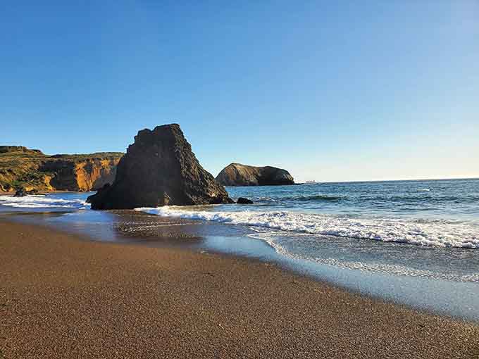 Gentle waves caressing distinctive rock formations at the water's edge, creating endless photo opportunities for patient visitors.