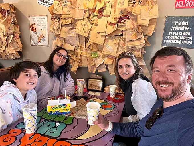 Happy diners beneath a wall of paper bag messages, because good food creates memories worth writing down.