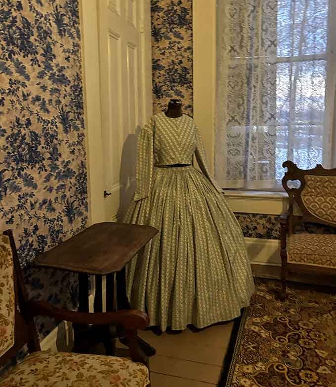 A period dress stands ready, as if its owner just stepped away and might return any moment to reclaim it.