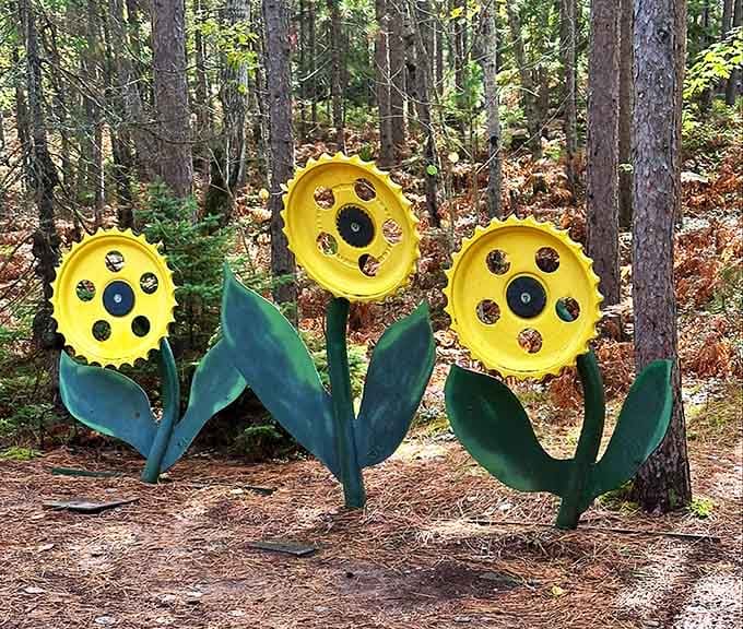 Metal sunflowers that never need watering, bringing perpetual sunshine to the forest floor in cheerful yellow and green.