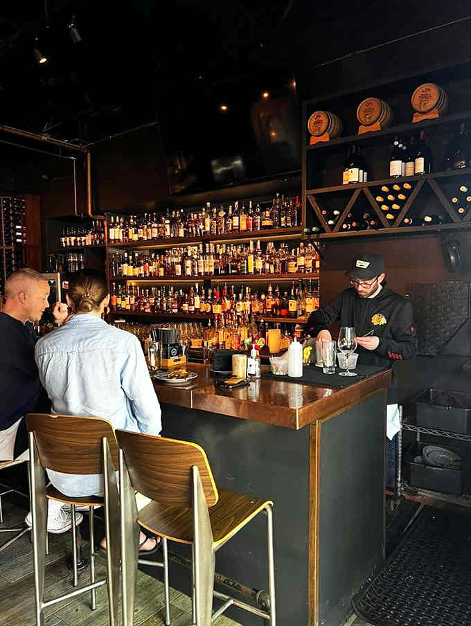 The bar buzzes with energy as skilled bartenders craft drinks with the precision of artists painting delicious masterpieces.