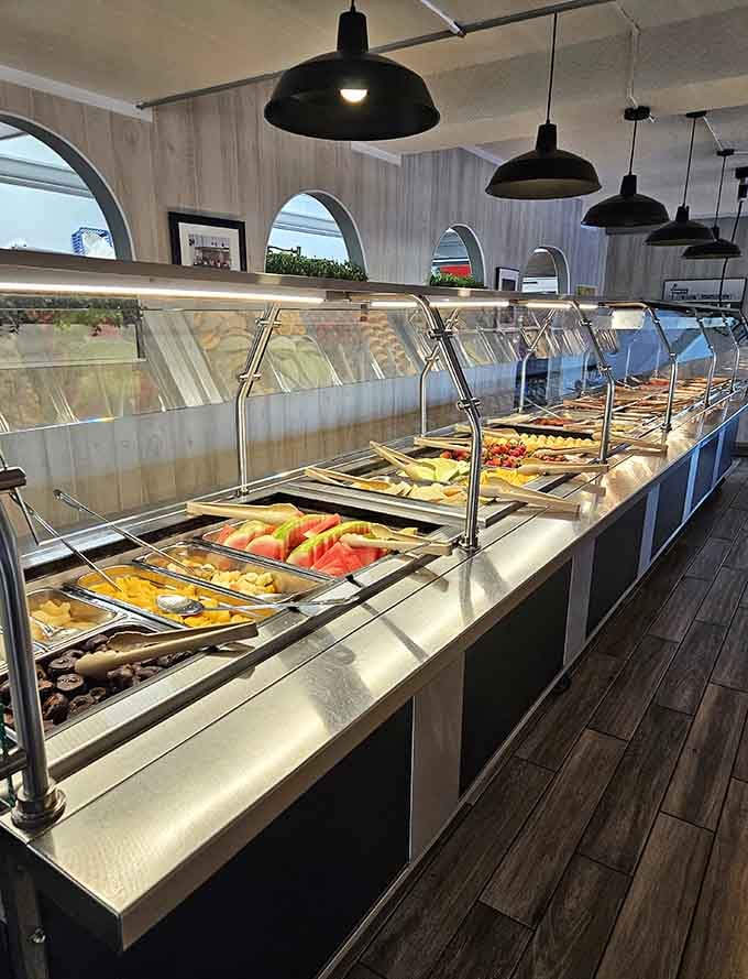 This buffet line stretches with hot breakfast options under warming lights, making decision-making deliciously difficult for hungry diners.