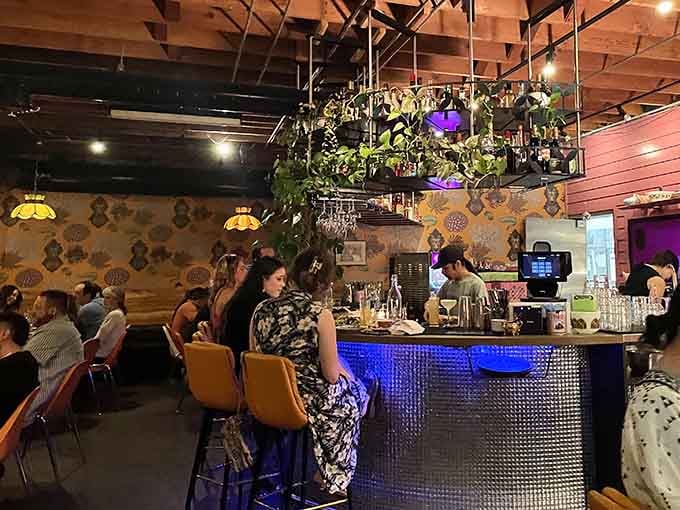 Lively bar scene with hanging plants overhead, proving that good food brings people together in the most delightful spaces.