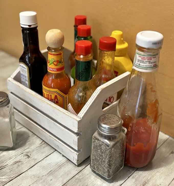 Hot sauce variety in a wooden caddy means they understand that everyone's heat tolerance is deeply personal.