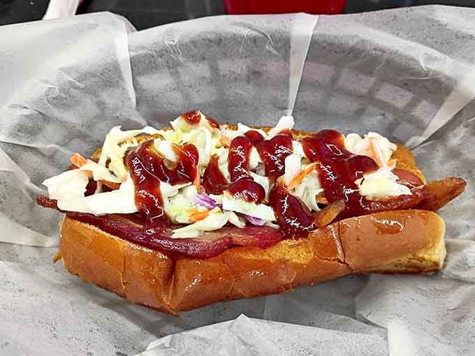 Bacon-wrapped hot dog drizzled with sauce and topped with slaw, because sometimes more is absolutely more.