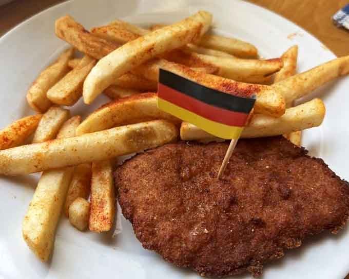 Crispy schnitzel with a tiny German flag planted proudly on top, staking its claim to authenticity one breaded cutlet at a time.