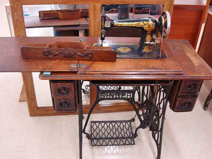 An antique sewing machine that's seen more fabric than a fashion designer's fever dream, still ready to stitch.