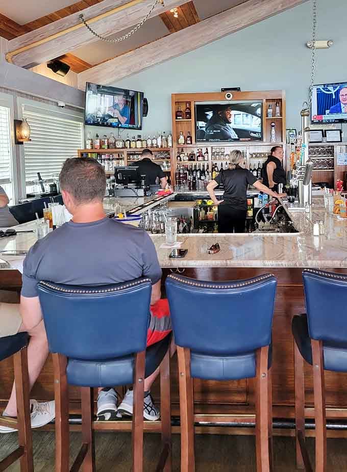The bar area buzzes with energy as bartenders craft drinks and diners settle in for harbor views and good times.