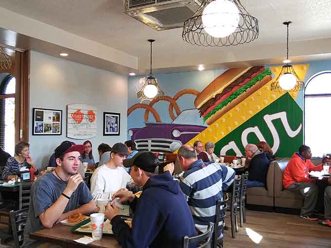 Families filling booths under that vibrant wall art prove that great food brings generations together around shared tables.