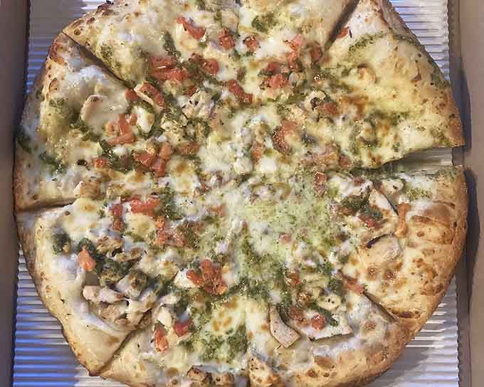 That pesto drizzle and those fresh toppings are giving serious gourmet vibes to this thin crust beauty.