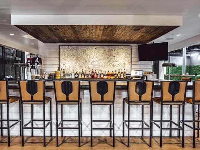 The bar stretches out with paddle-shaped stools, because even the furniture gets into the pickleball spirit here.