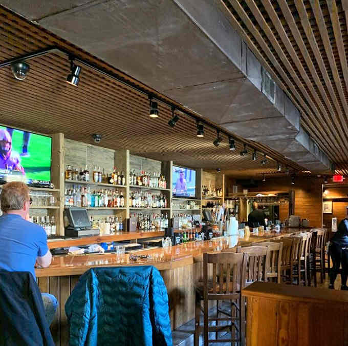 The polished bar gleams beneath modern screens, blending contemporary convenience with old-world charm in perfect harmony for today's guests.