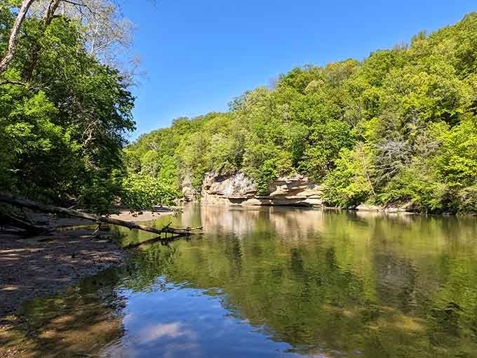 Sugar Creek's glassy surface reflects towering cliffs, offering paddlers and swimmers a liquid mirror of geological magnificence.