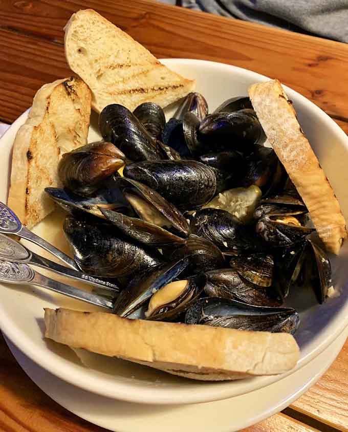 Mussels swimming in garlic wine sauce with grilled bread for dunking equals pure shellfish happiness in a bowl.