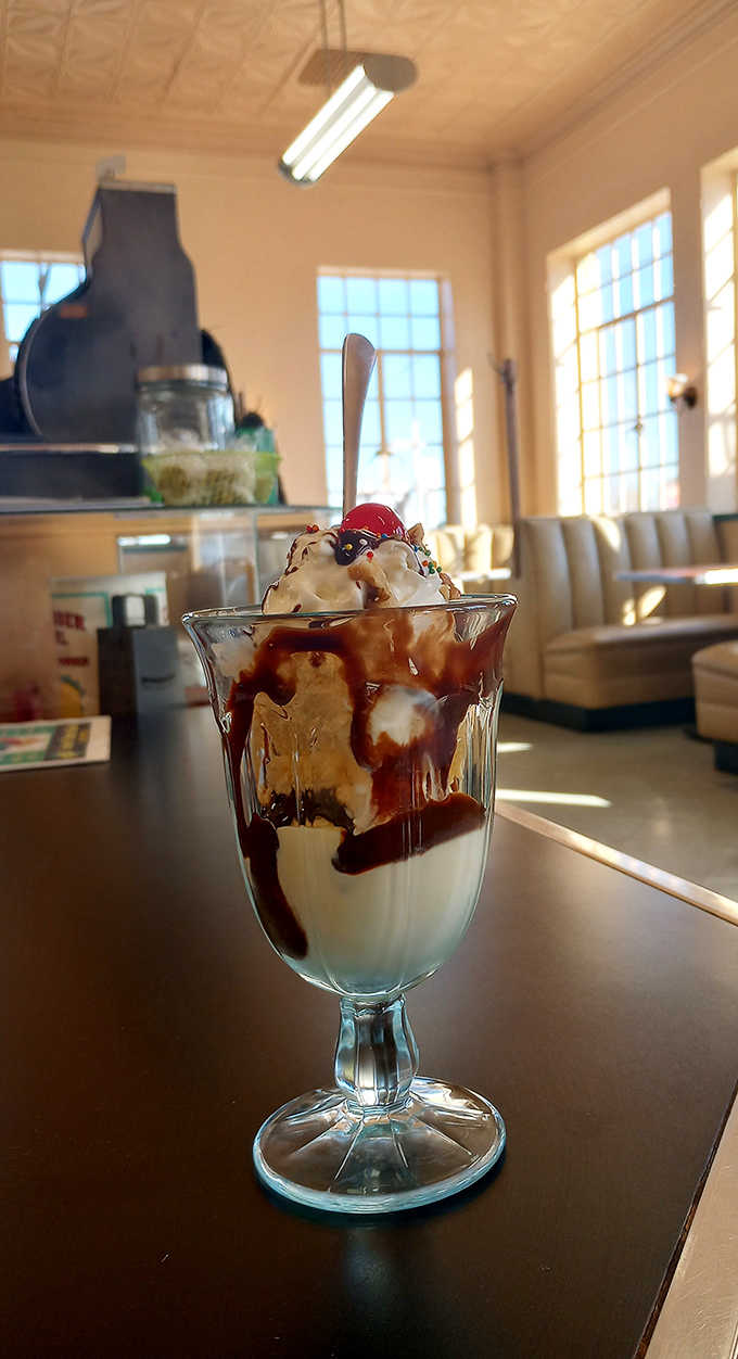 Ice cream sundaes towering in classic glassware, drizzled with chocolate sauce and topped with cherries like grandma remembers them.