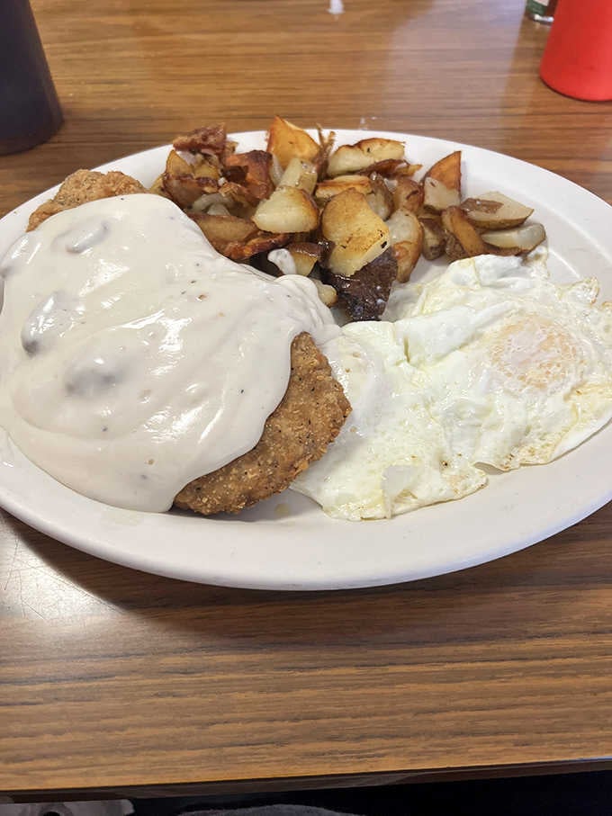 Chicken fried steak smothered in gravy alongside eggs and hash browns, the breakfast of Midwestern champions.