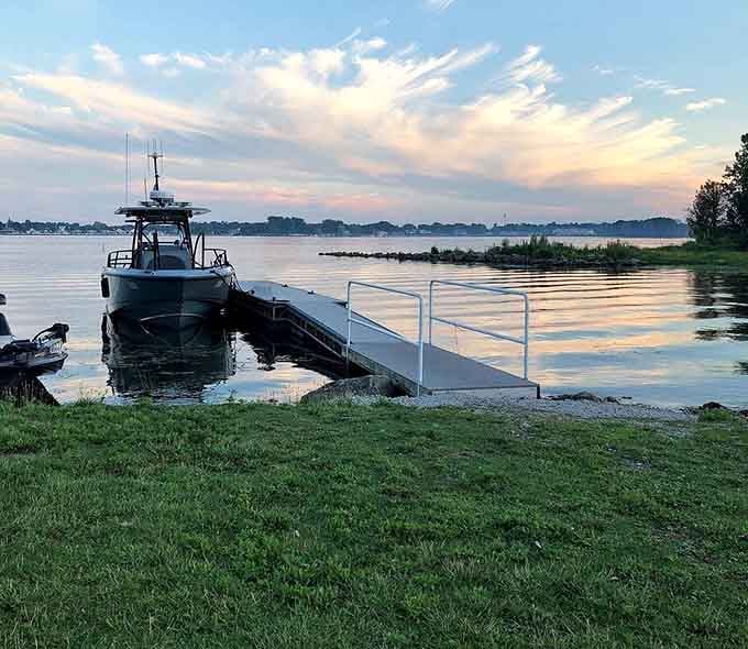 Sunset-painted skies reflecting off calm waters where boats rest easy after a day of Lake Erie adventures.