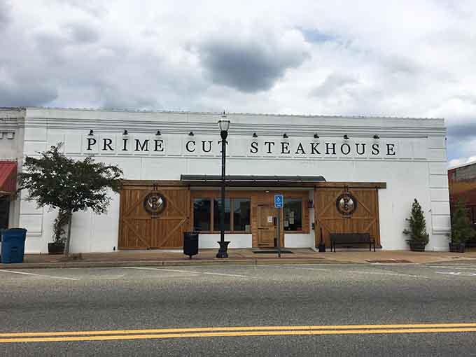 The crisp white facade with rustic barn doors creates an intriguing contrast that makes you curious about dinner.