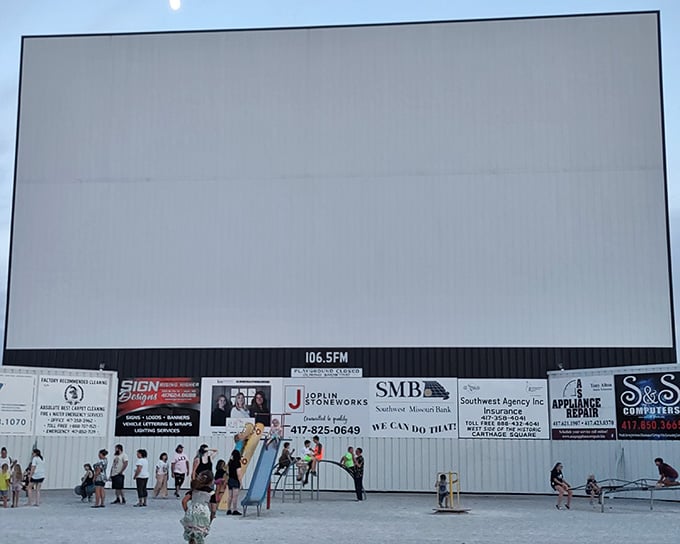 Kids play on the playground equipment as dusk approaches, burning energy before settling in for the main attraction ahead.