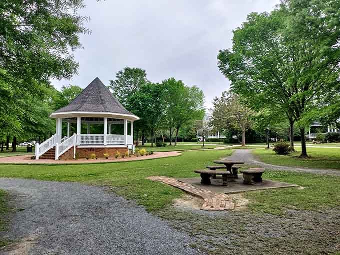 The white gazebo sits peacefully among towering trees, offering shade and Southern hospitality in equal measure to weary visitors.
