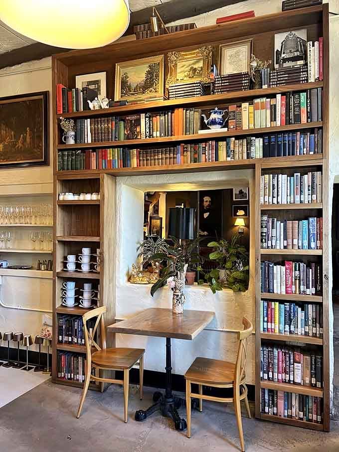 Books frame a cozy table nook where you can disappear into stories while your sandwich disappears from your plate.