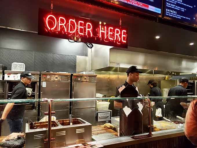 That red "ORDER HERE" sign means business, and behind it, magic happens in the form of slow-smoked meats.