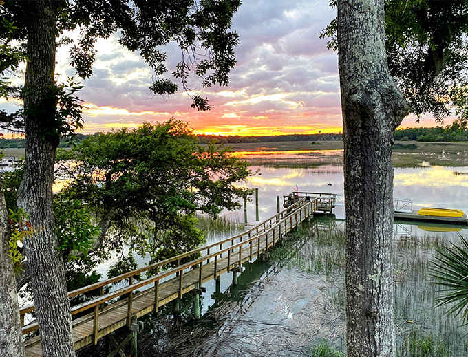 Sunset paints the marsh in cotton-candy hues while a weathered dock leads straight into the golden hour.