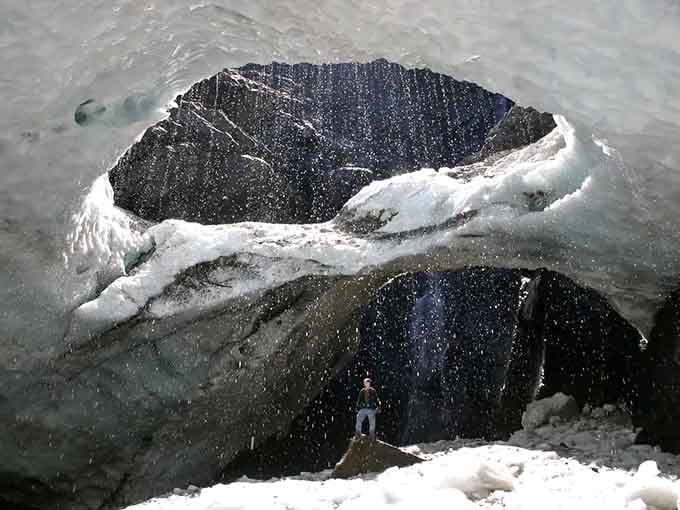 Scale becomes clear when tiny humans stand before this frozen giant, nature's reminder of our place.