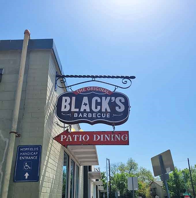 The sign pointing to patio dining promises fresh air and sunshine to accompany your smoky feast.