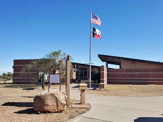 The visitor center welcomes guests with flags flying proud, ready to share secrets about this remarkable landscape.