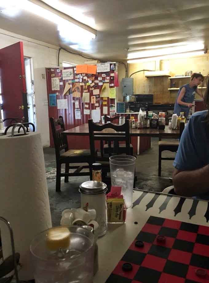 The no-frills interior with its bulletin board of memories and open kitchen view adds to the authentic small-town diner charm.