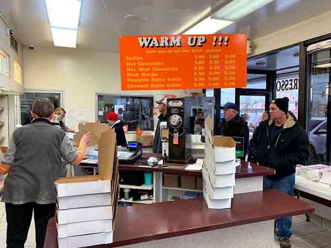 Customers queue up at the counter where important decisions about chocolate versus glazed happen under fluorescent wisdom lights.