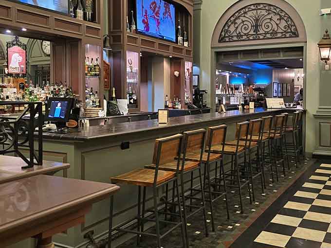 That long wooden bar with its checkered floor and rows of stools is where strangers become friends over shared appetizers and cold drinks.