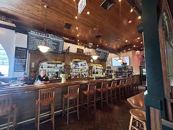 The long bar with brewing tanks visible behind glass, where watching beer being made enhances drinking it.
