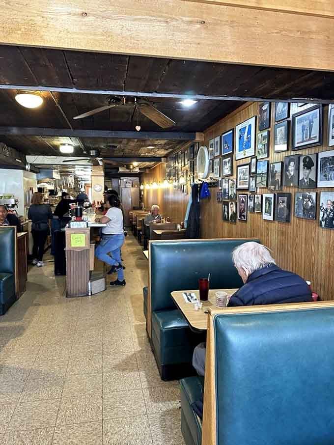 Vintage photographs line the walls above green vinyl booths, creating a gallery of memories while you enjoy your meal.