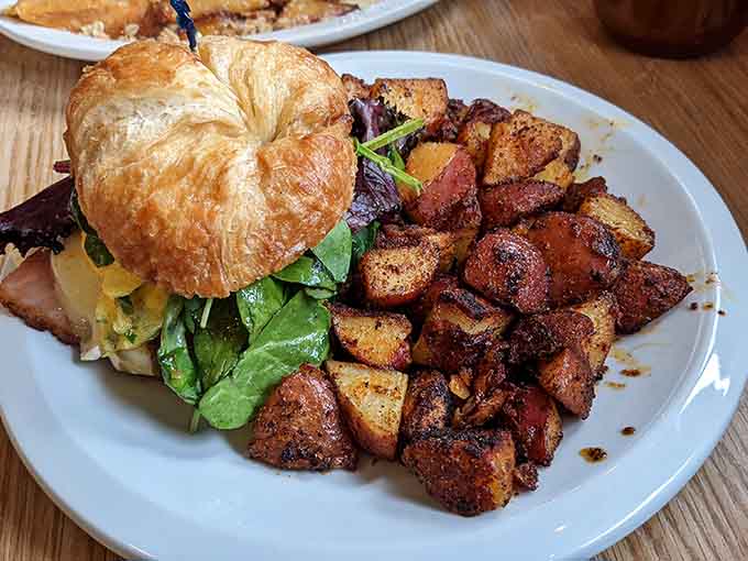 This breakfast sandwich on a flaky croissant with seasoned potatoes understands that presentation matters, even at brunch.