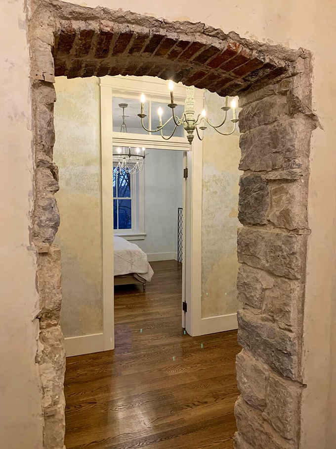 Raw stone framing and exposed brick overhead create doorways that feel like portals to another century entirely.