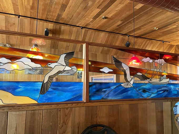 Stained glass seabirds soaring over ocean waves bring artistic beauty to every booth in the restaurant.