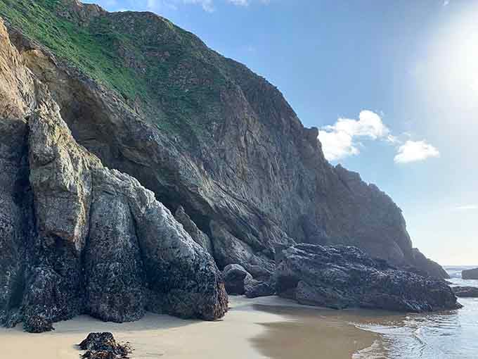 Towering cliff walls at low tide reveal geological layers that make you appreciate Earth's patient artistry.