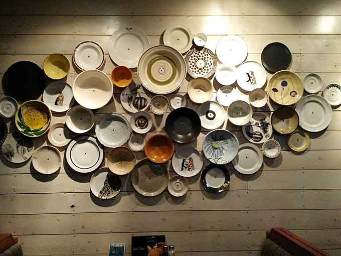 That eclectic wall of vintage plates is like dining inside someone's very cool grandmother's collection.