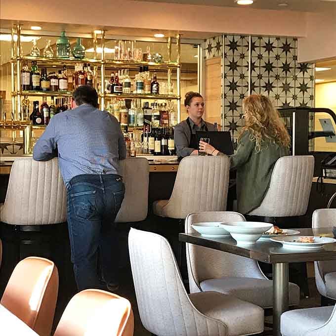 The bar beckons with its gleaming bottles and mid-century modern stools, inviting you to settle in awhile.