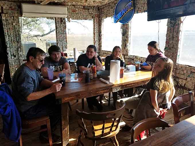 Families gathering around wooden tables, making memories one crab cake at a time in dollar-covered comfort.